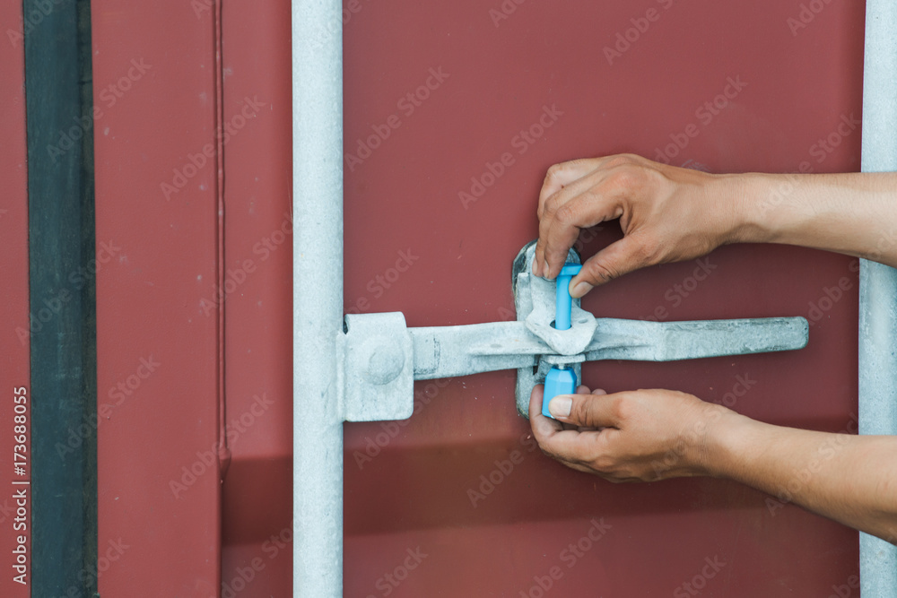 hand of worker attend to door locking handle with bolt sealing tie ...