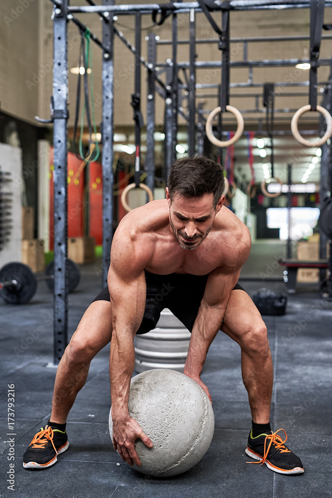 Man carrying a atlas stone in a gym Stock Photo | Adobe Stock