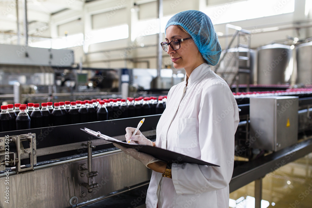 Serious middle age woman quality control worker checking robotic line ...