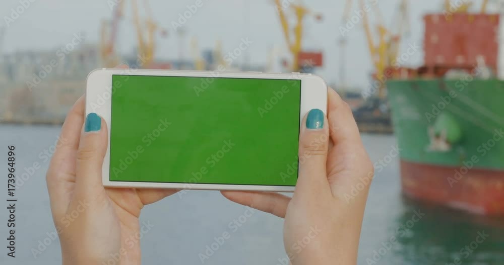 Close up front view woman hands holding white smartphone outside port ...