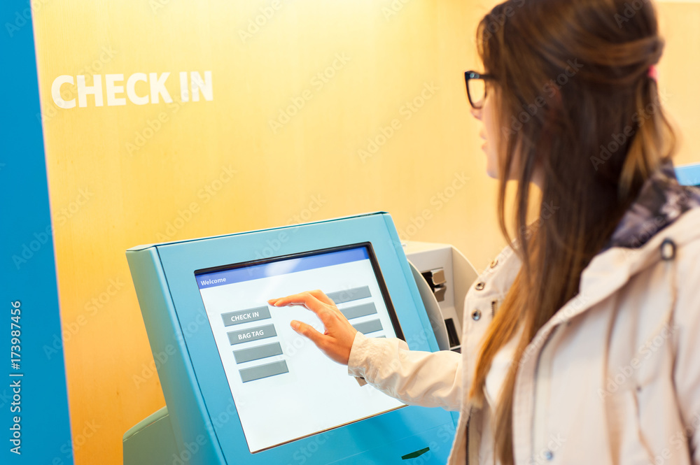 Young woman at self service transfer area doing self-check-in at ...