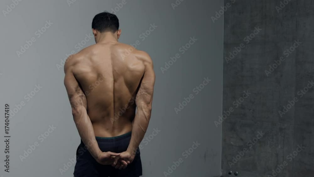 A fitness model displays and flexes his sculptured back muscles. Medium ...