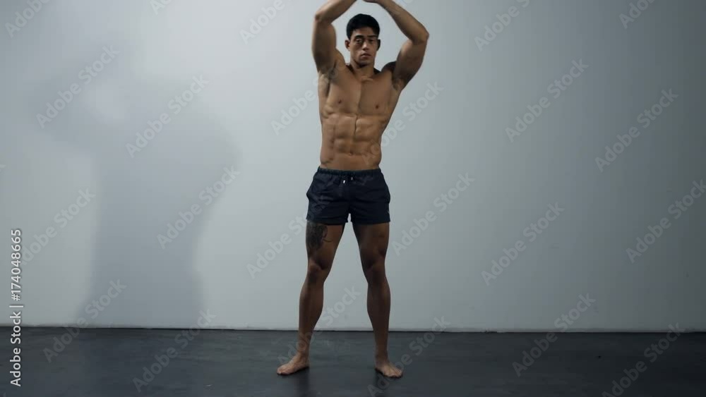A fitness model displays his triceps and biceps by stretching his arms ...