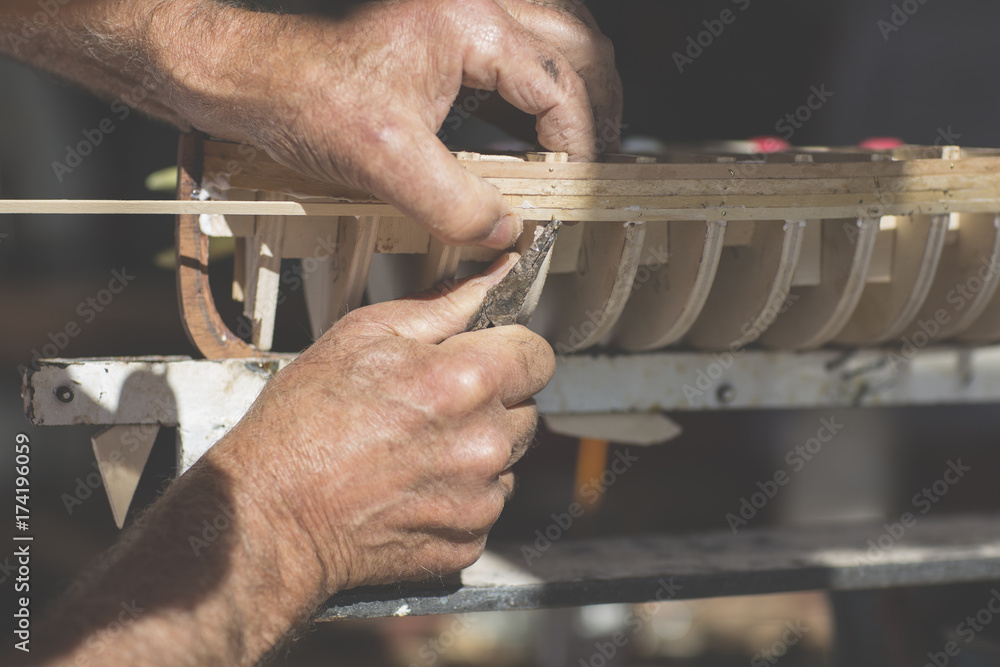 handcrafted craftwork of a wooden boat model / old man working on ...