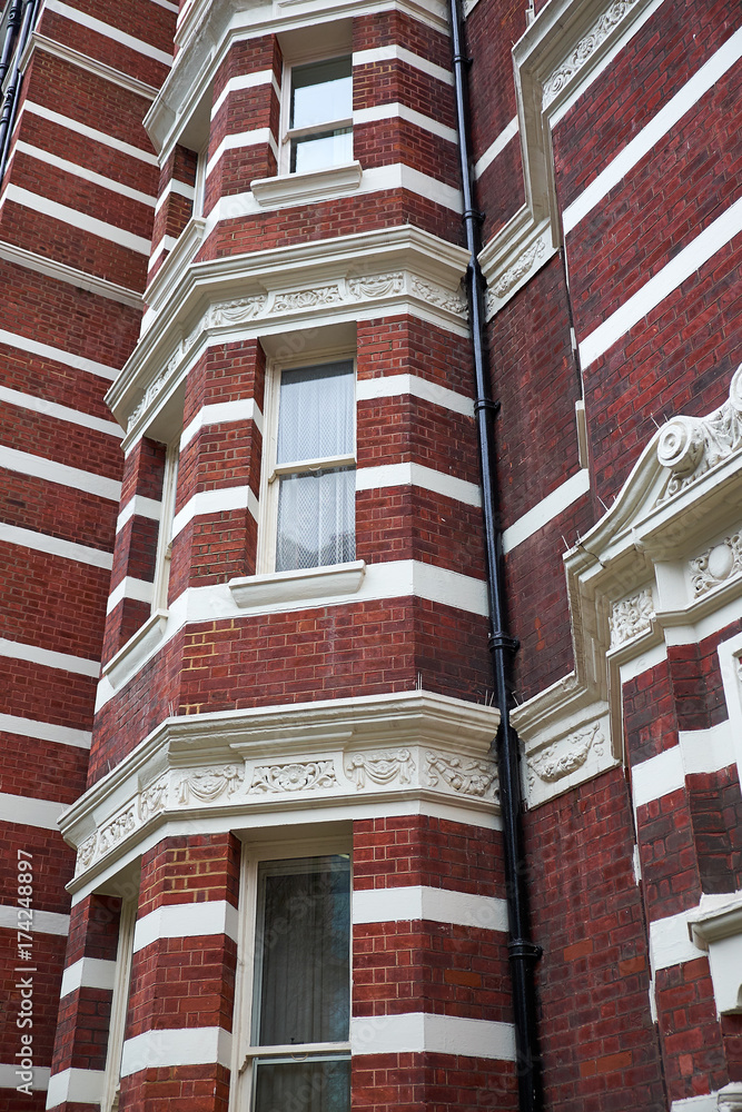 Hung bay windows in a London residential building facade of red bricks ...