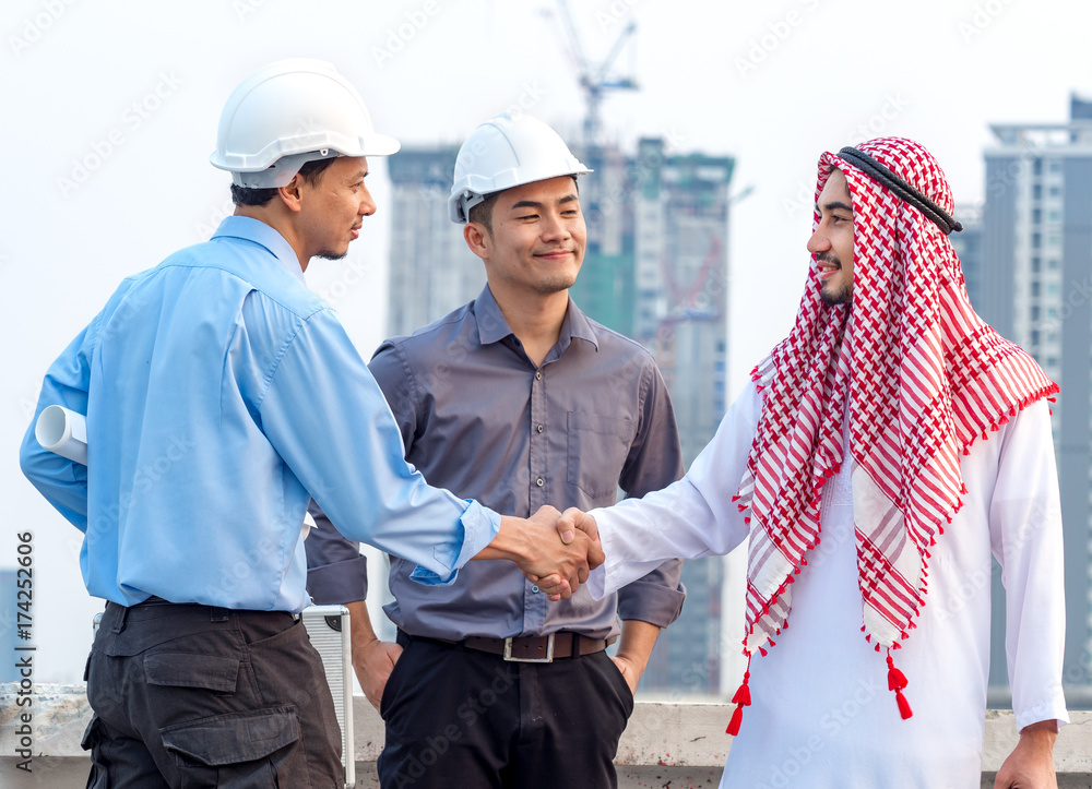 Young asian engineer/architect shaking hands with arab businessman ...