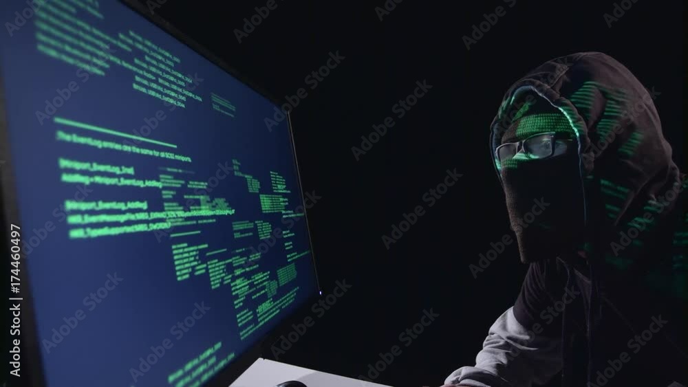 Spy hacking computer sitting in a dark room. Black background Stock Video | Adobe Stock