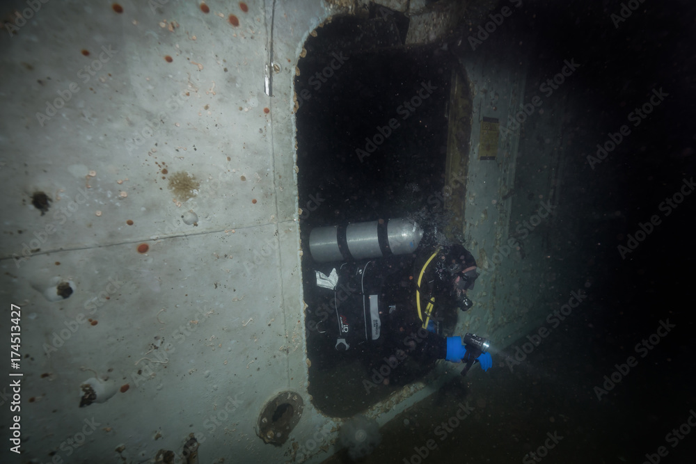 Underwater picture of a scuba diver exploring a sunken wreck ship ...