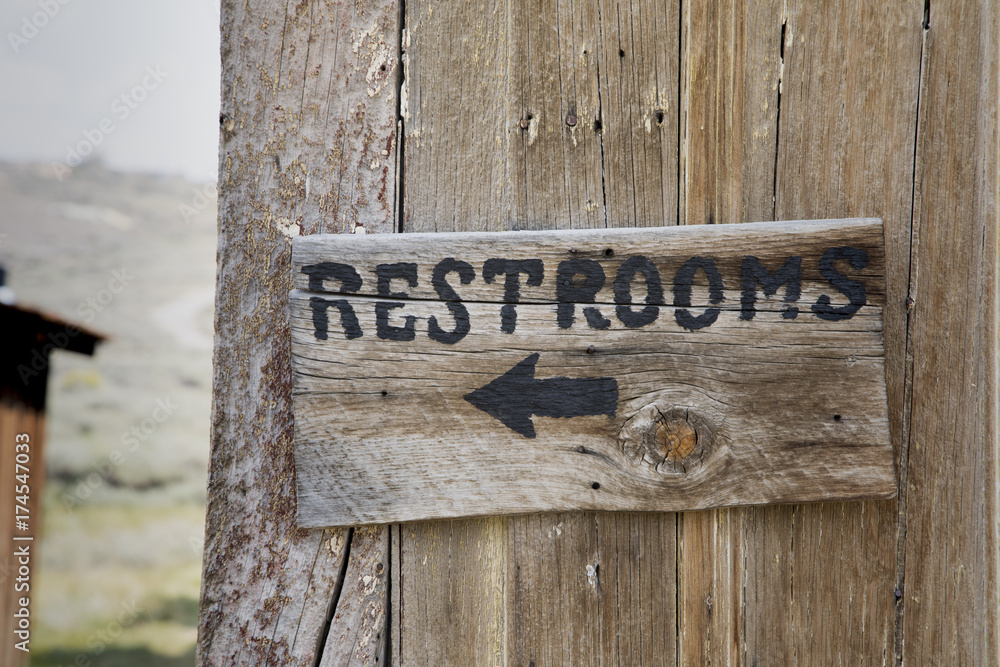 An old, wooden restroom sign with arrow on the side of a building Stock ...