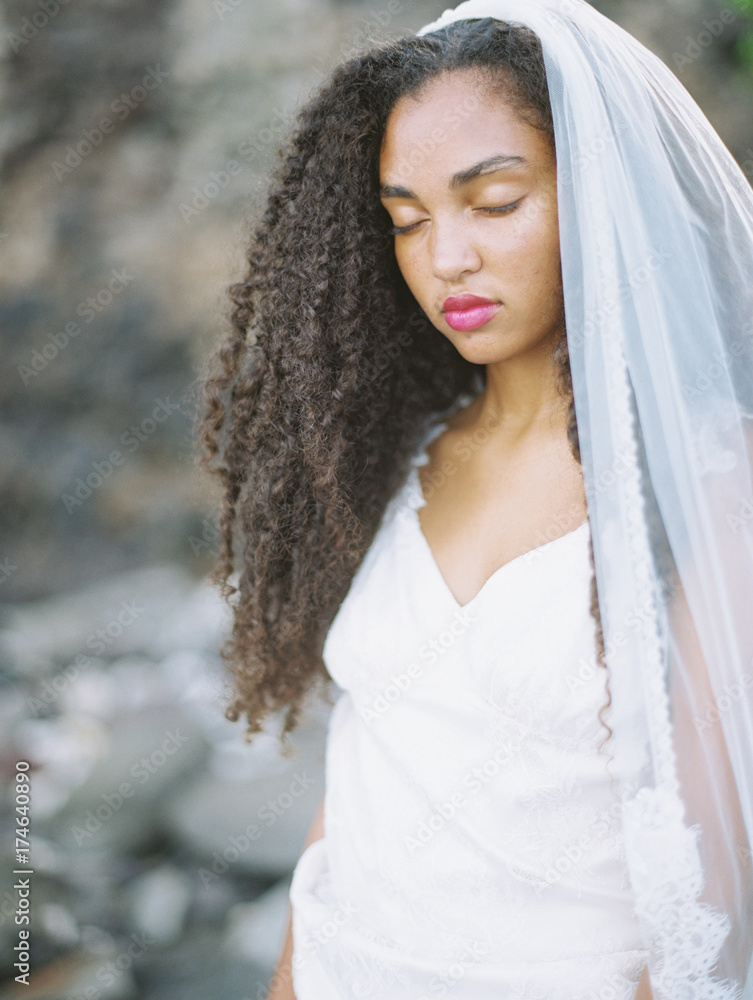 beautiful black bride on beach in gorgeous wedding gown with rocks and ...
