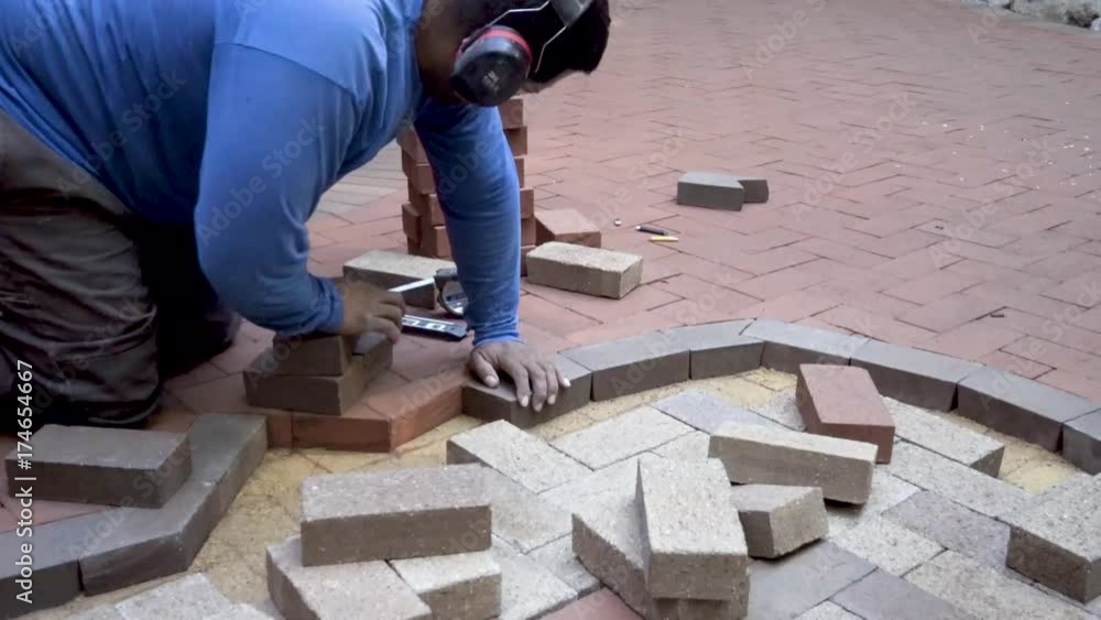 Brick paving expert fits brick paver into place and measures it and ...