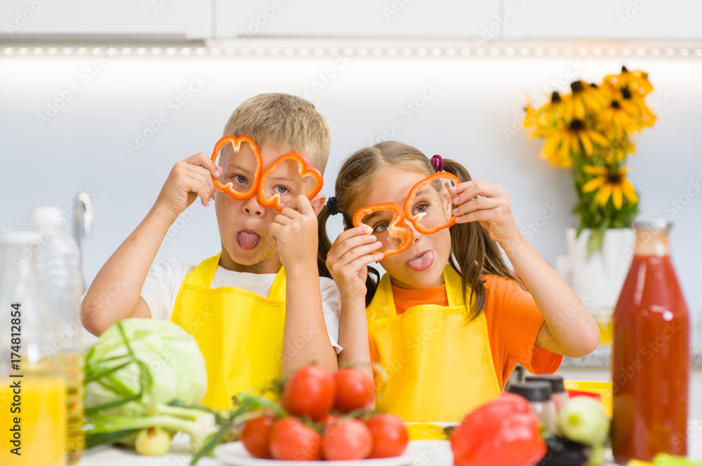 Happy kids having fun with food vegetables at kitchen holds pepper ...