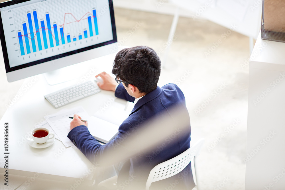 Contemporary financial specialist sitting by workplace in front of ...