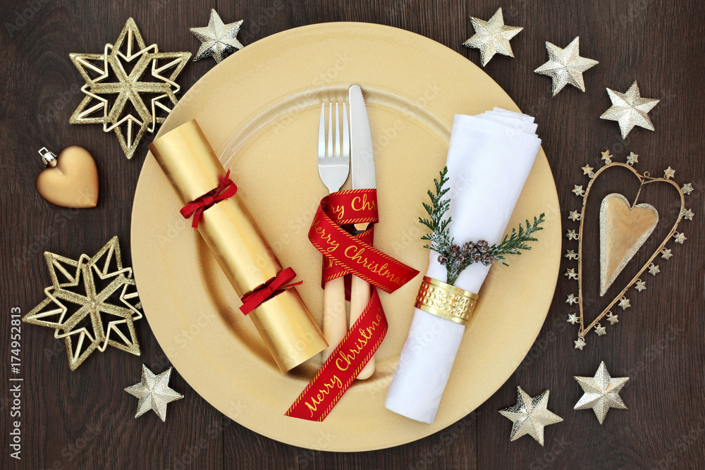 Christmas dinner place setting with gold plate, cutlery with red ribbon ...
