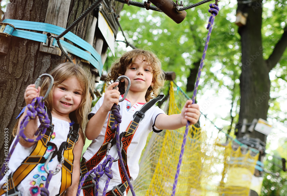children - a boy and a girl in the rope park pass obstacles. Brother ...