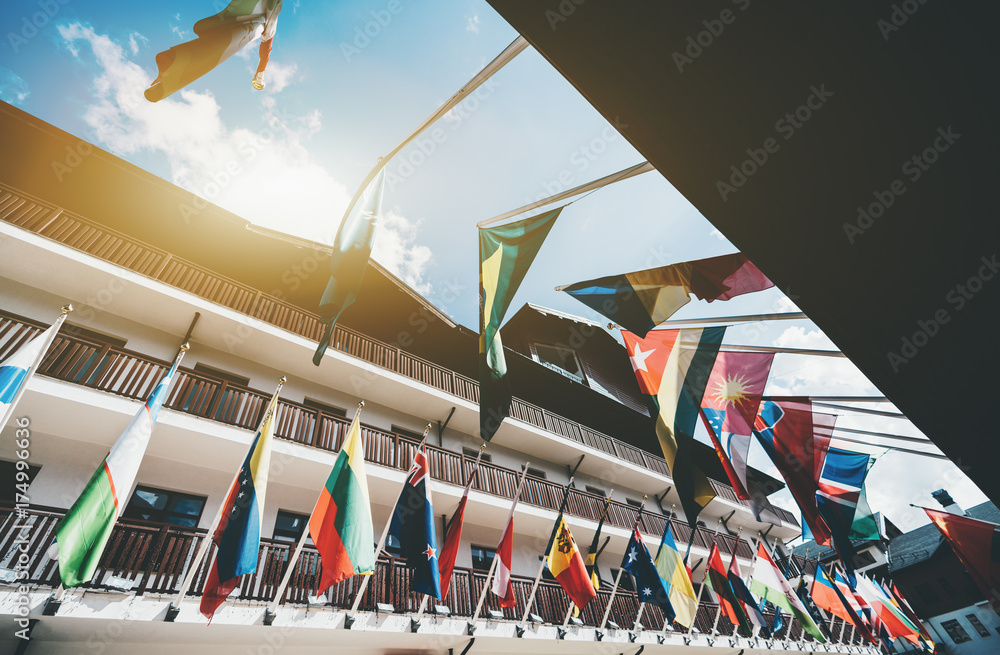 Wide-angle view of buildings facades with multiple national flags of ...