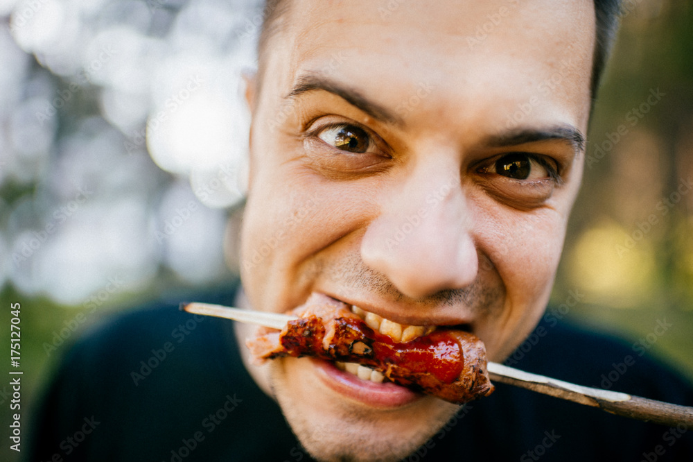Closeup portrait of male licking and biting roasted sausage with ...