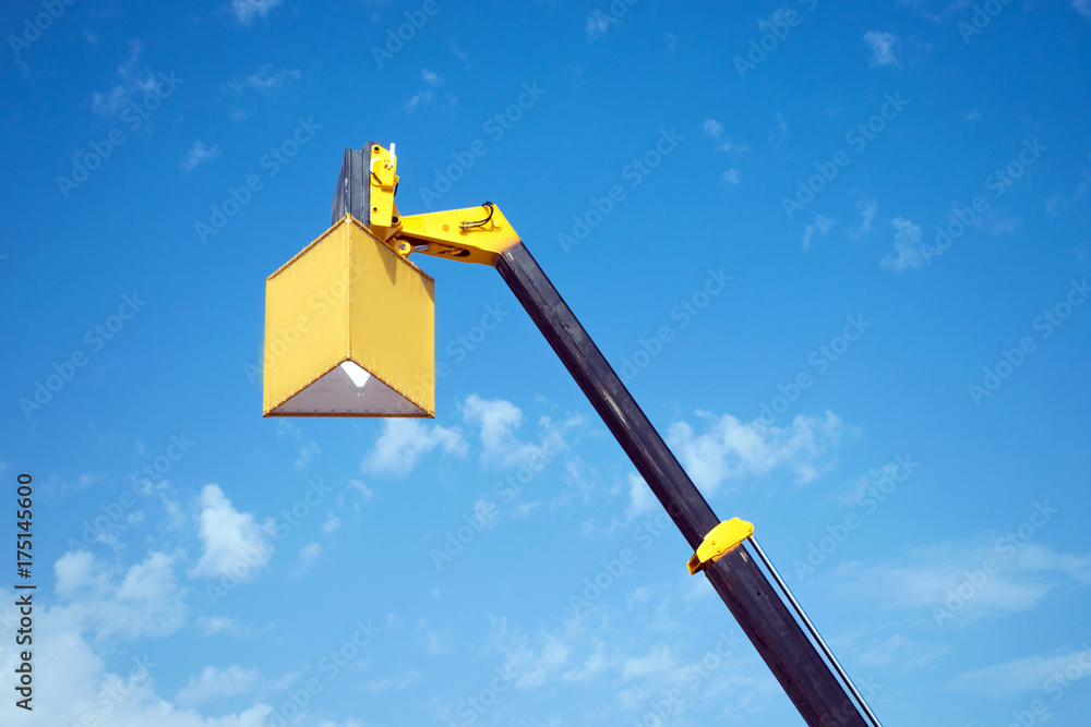 Raised yellow boom of mobile crane with a suspended cube for ...