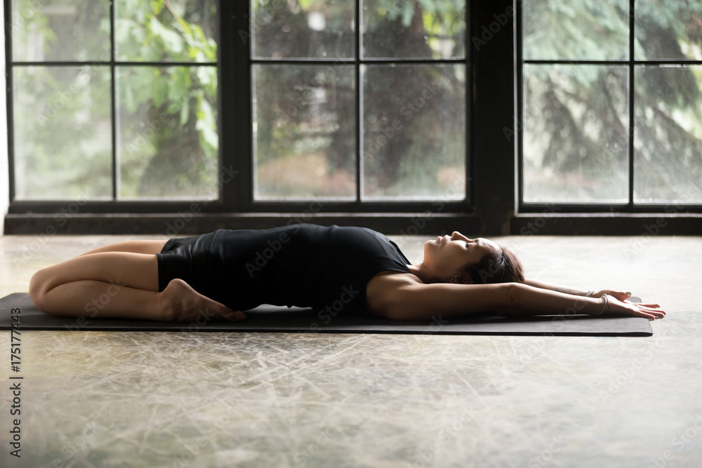 Young attractive woman practicing yoga at home, stretching in Reclining ...
