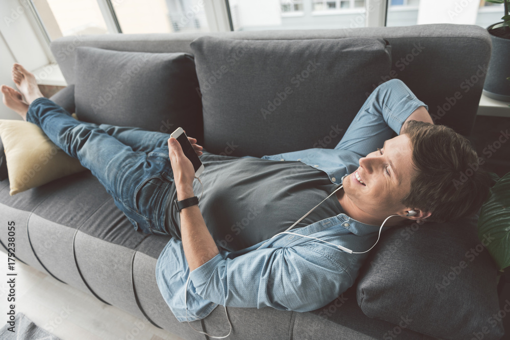 Outgoing male hearing song on sofa Stock Photo | Adobe Stock