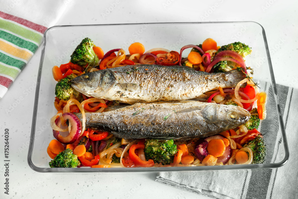 Baking tray with tasty fish and vegetables on kitchen table Stock Photo ...
