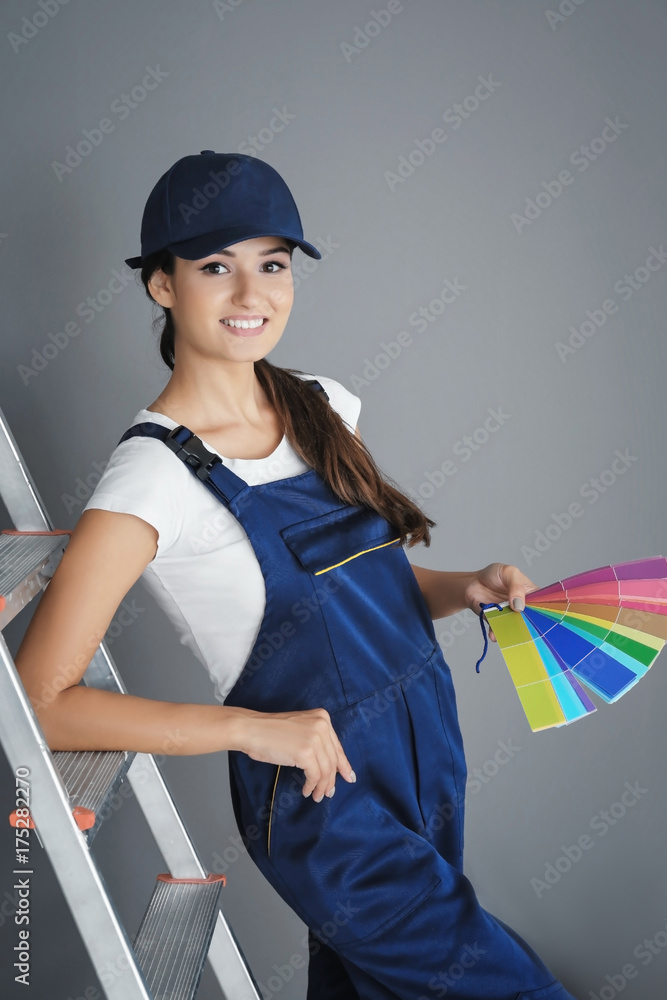 Young female decorator with color palette samples near ladder against ...