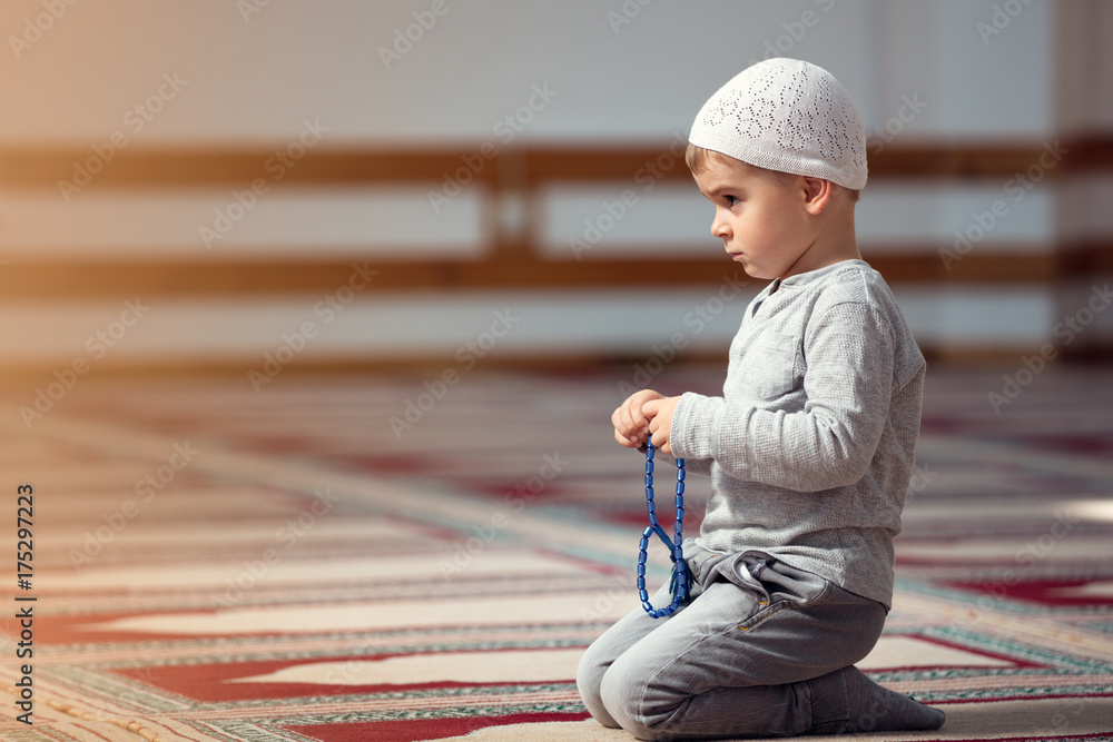 The Muslim child prays in the mosque, the little boy prays to God ...