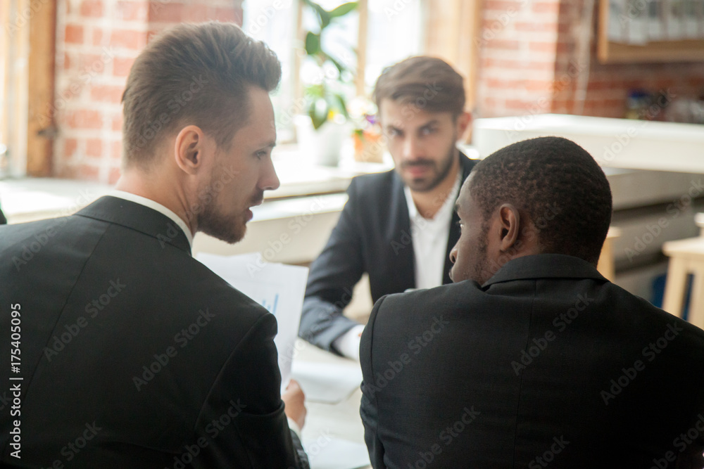 Rear view of serious boss holding financial stats report and scolding ...
