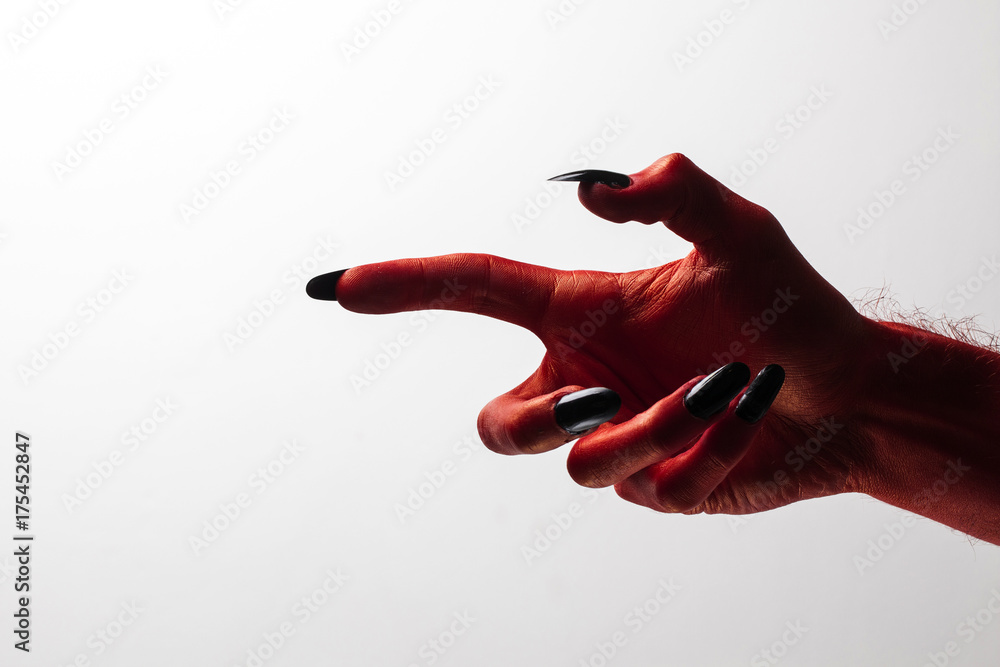 Halloween red devil monster hand with black fingernails against a plain ...