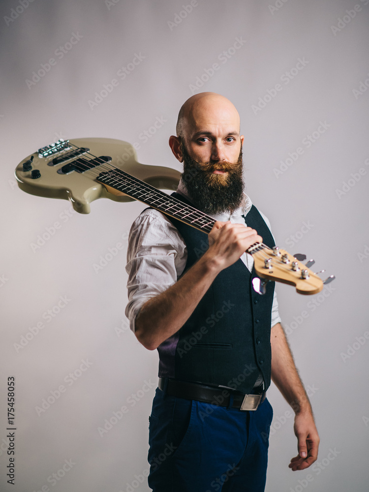 bearded man holding a guitar on his shoulder and looking at the camera ...