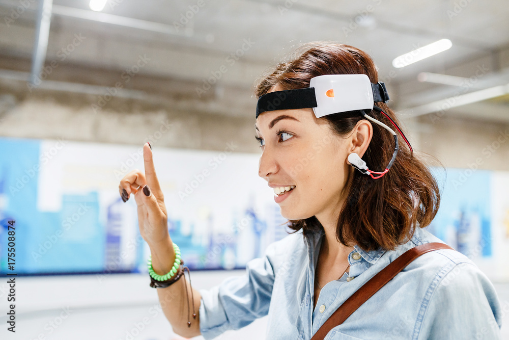 Woman with digital headset sensor connected to her ear, reading brain ...