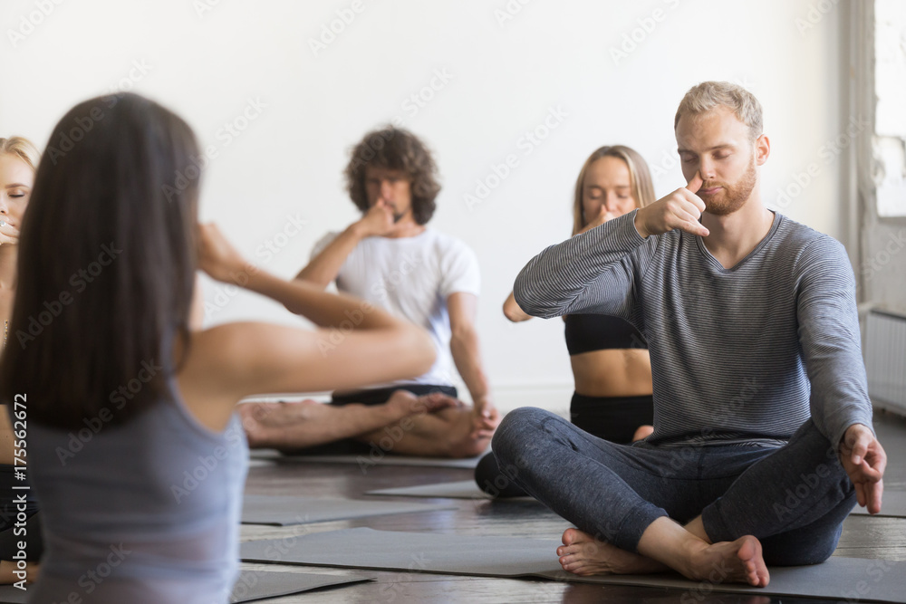 Group of young sporty people practicing yoga lesson with instructor ...