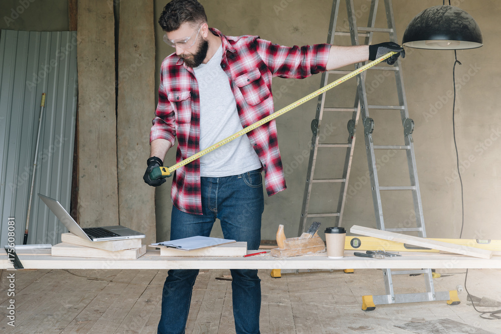 The man is a carpenter, a builder, a designer stands in the workshop ...