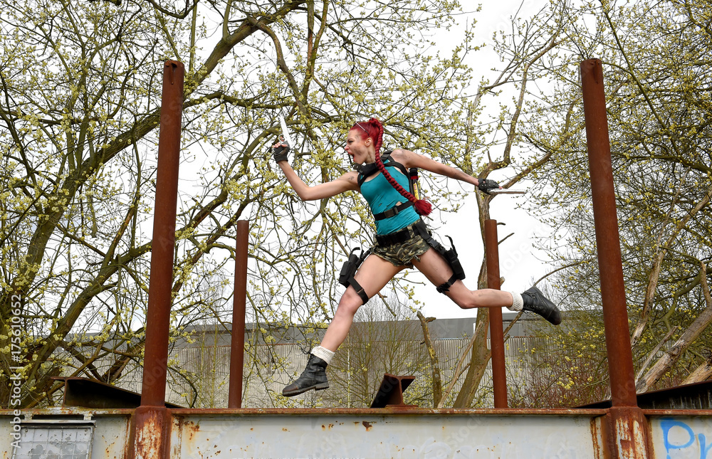 A young girl gets dressed as an actionwoman. She poses outdoors and ...