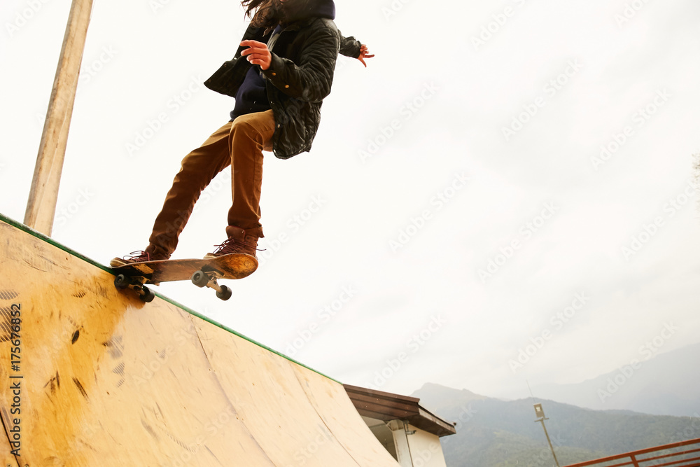 A guy skateboarder skating on a wet ramp doing tricks in the mountains ...