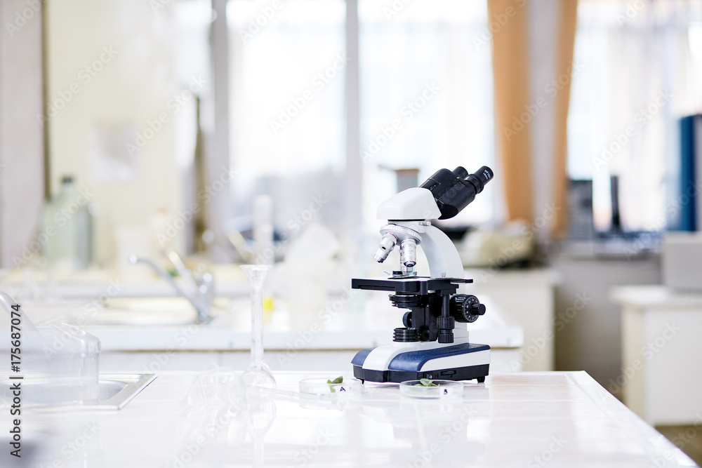 Modern binocular microscope and laboratory glassware prepared for ...