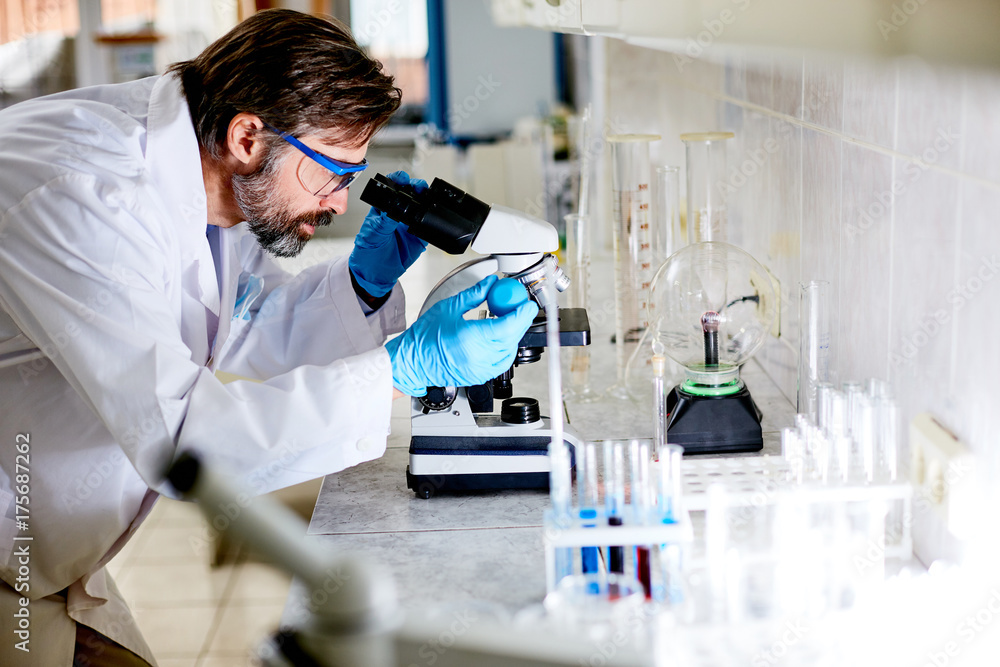 Profile view of bearded middle-aged researcher wearing white coat and ...