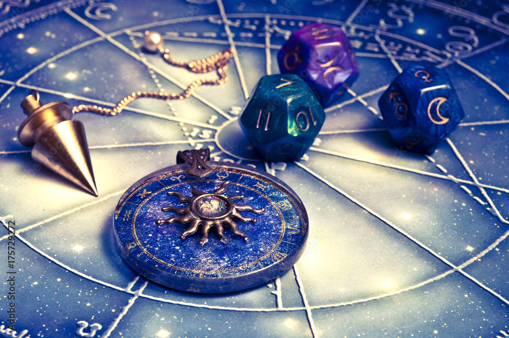zodiac ring, pendulum, dice with astrology symbols lying on horoscope ...