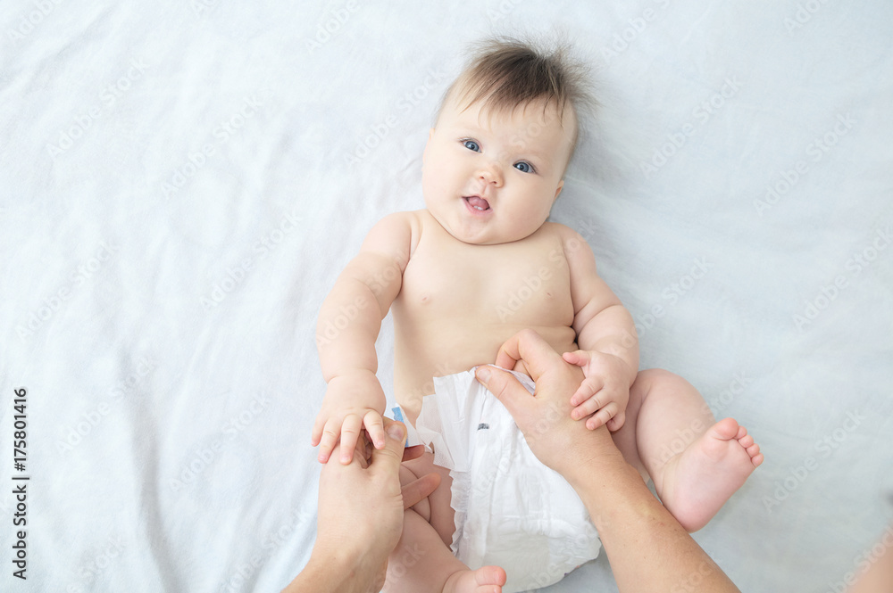 changing diaper on baby girl on bed, changing nappy, everyday care ...