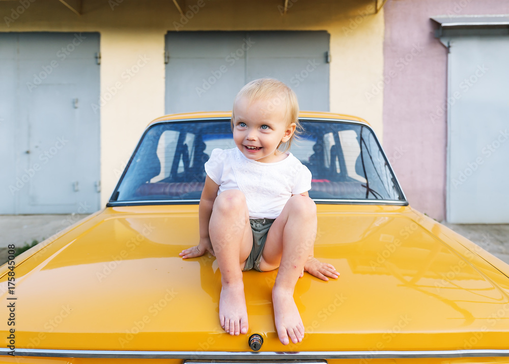 Little girl sitting on yellow car roof. Stock Photo | Adobe Stock
