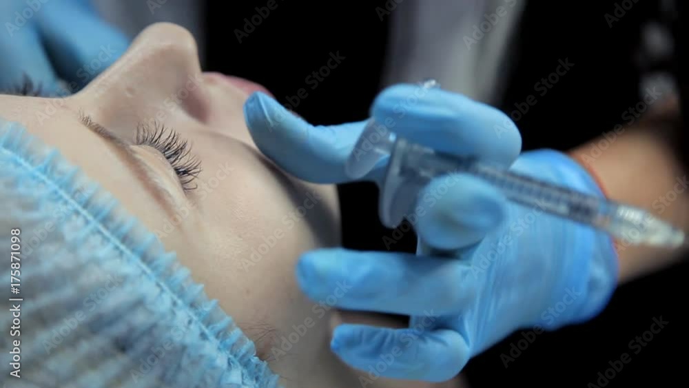 The beautician smoothes botox in the lips of a young girl after the ...