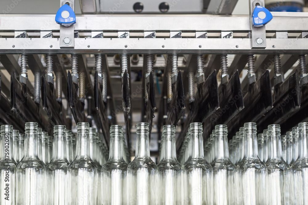 A pneumatic manipulator unloads empty glass bottles from a cardboard ...