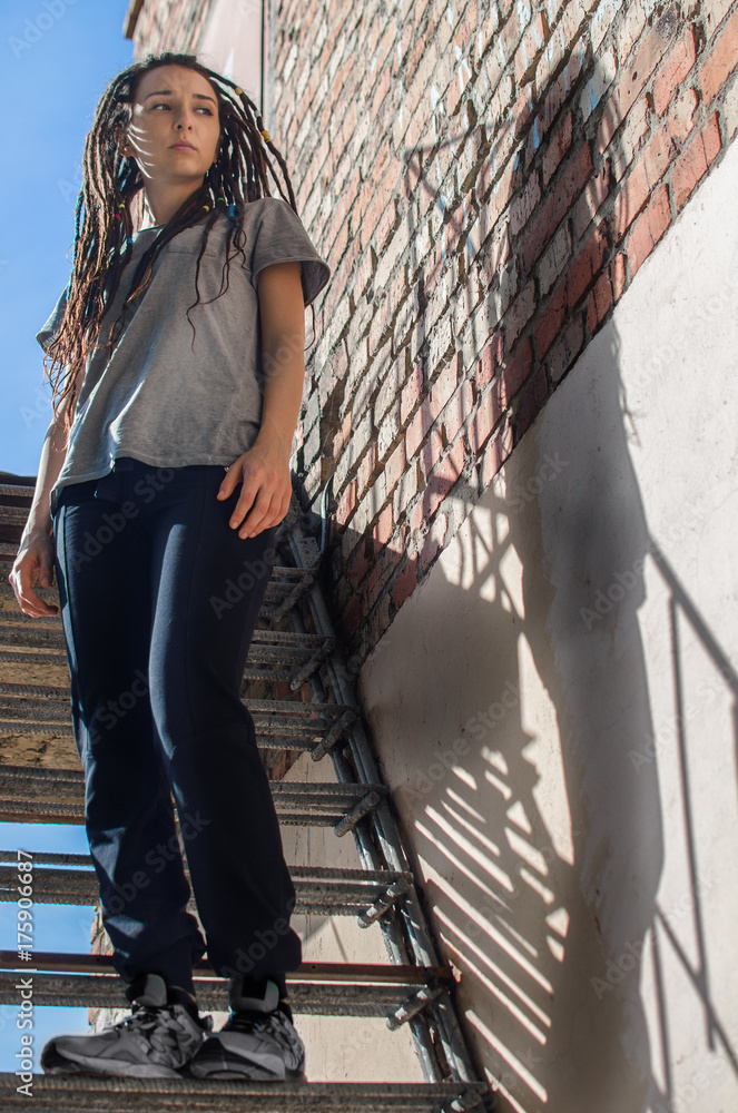 Beautiful girl with dreadlocks in hard light with shadows of metal ...