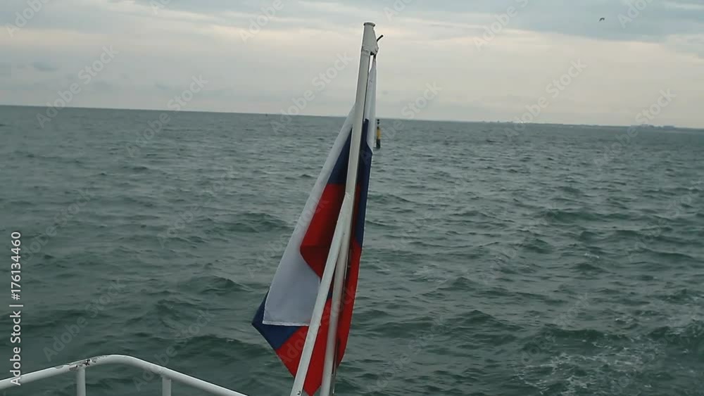Russian flag waving in the background of the glare on the water. Stern ...