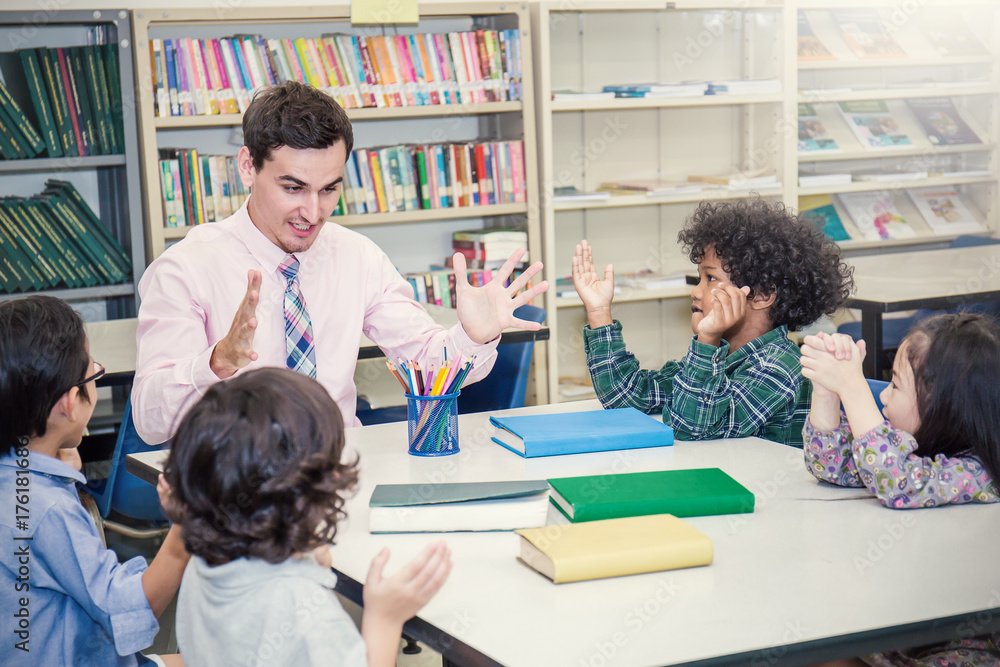 Pupils studying with teacher at desks in classroom, Teacher and little ...