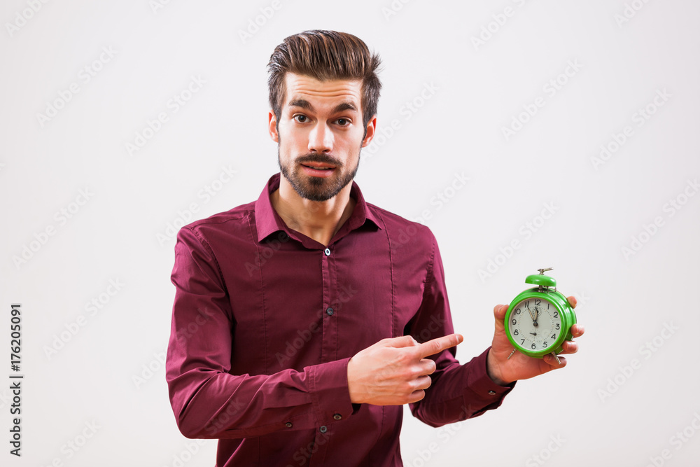 Young businessman is pointing at clock that shows five to twelve time ...