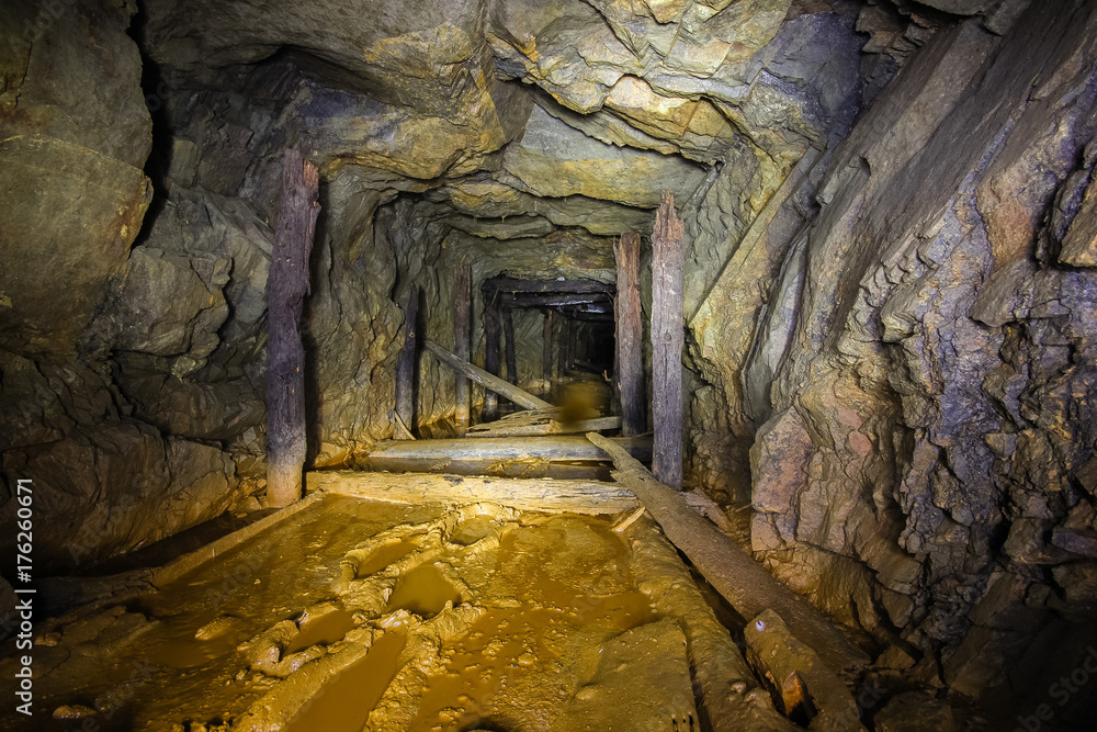 Undreground abandoned old mine shaft tunnel gallery passage with wooden ...