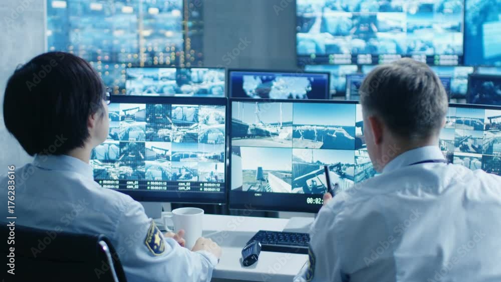 In the Security Control Room Two Officers Monitoring Multiple Screens ...