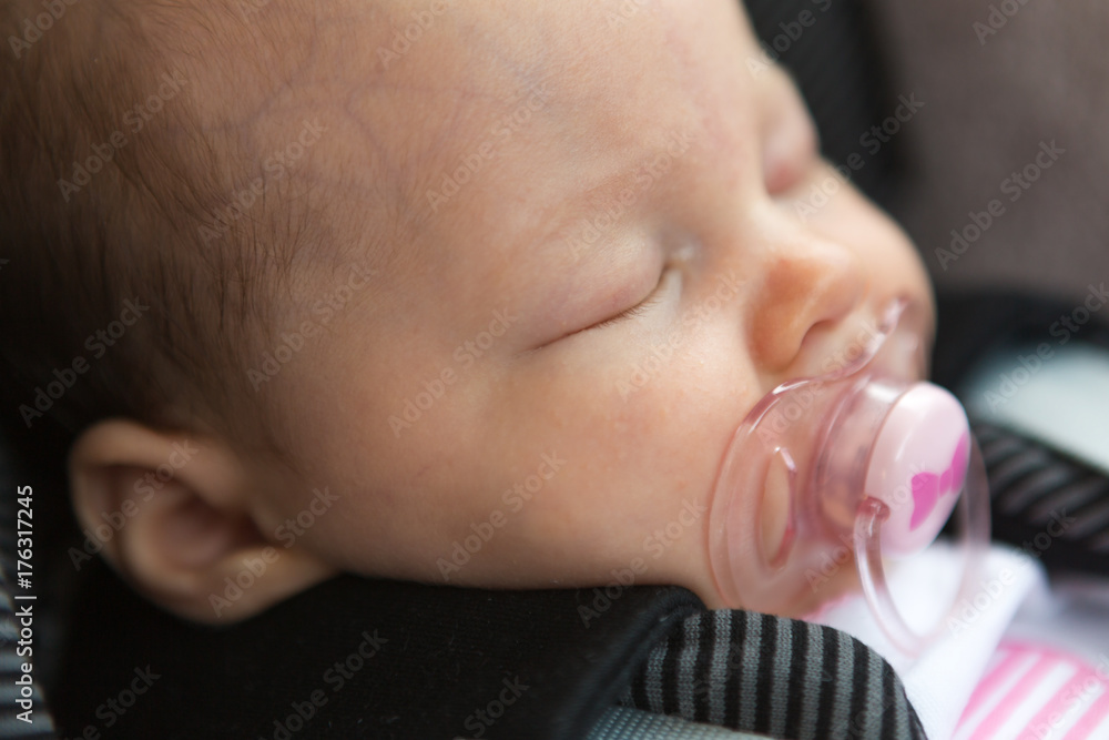 Seven months old baby girl sleeping in the car safety seat with the ...