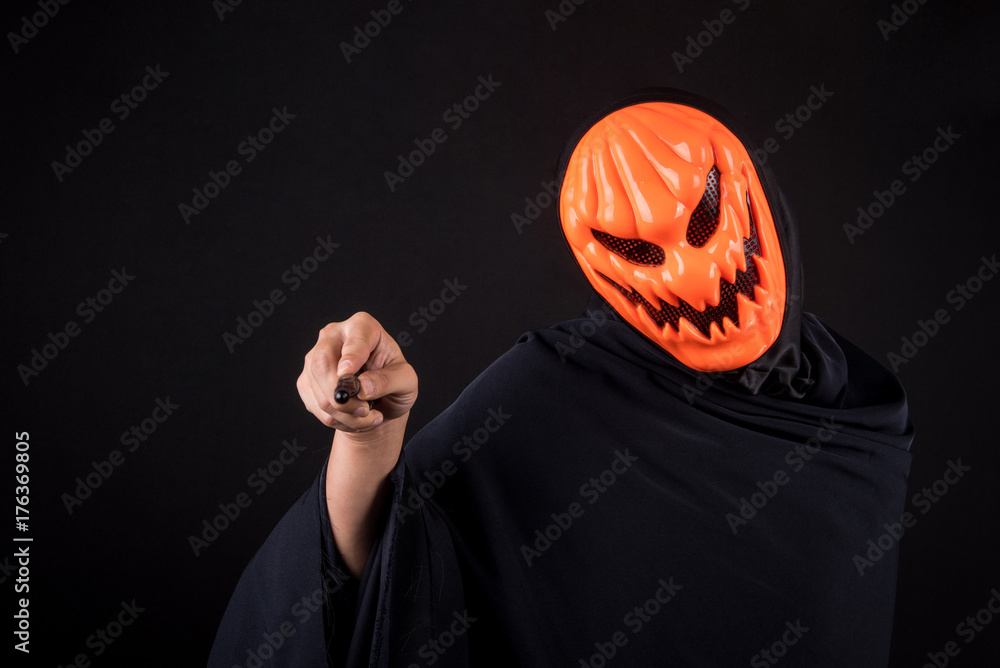 Mystery man with orange pumpkin evil mask holding magic wand on black ...